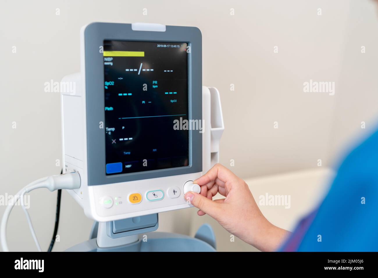 Doctor operating vital sign monitor in patient room of modern hospital ...