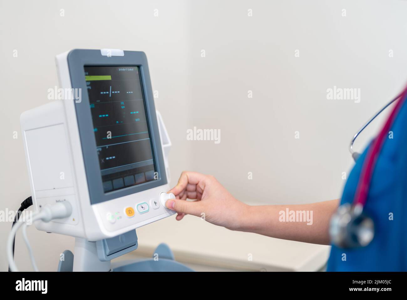 Doctor operating vital sign monitor in patient room of modern hospital ...