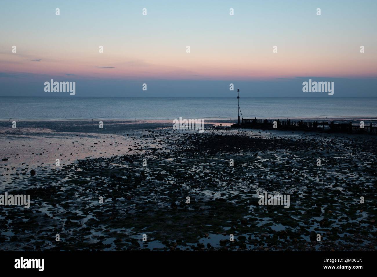 Sea groynes and reflected light over Hunstanton beach at sunset Stock ...