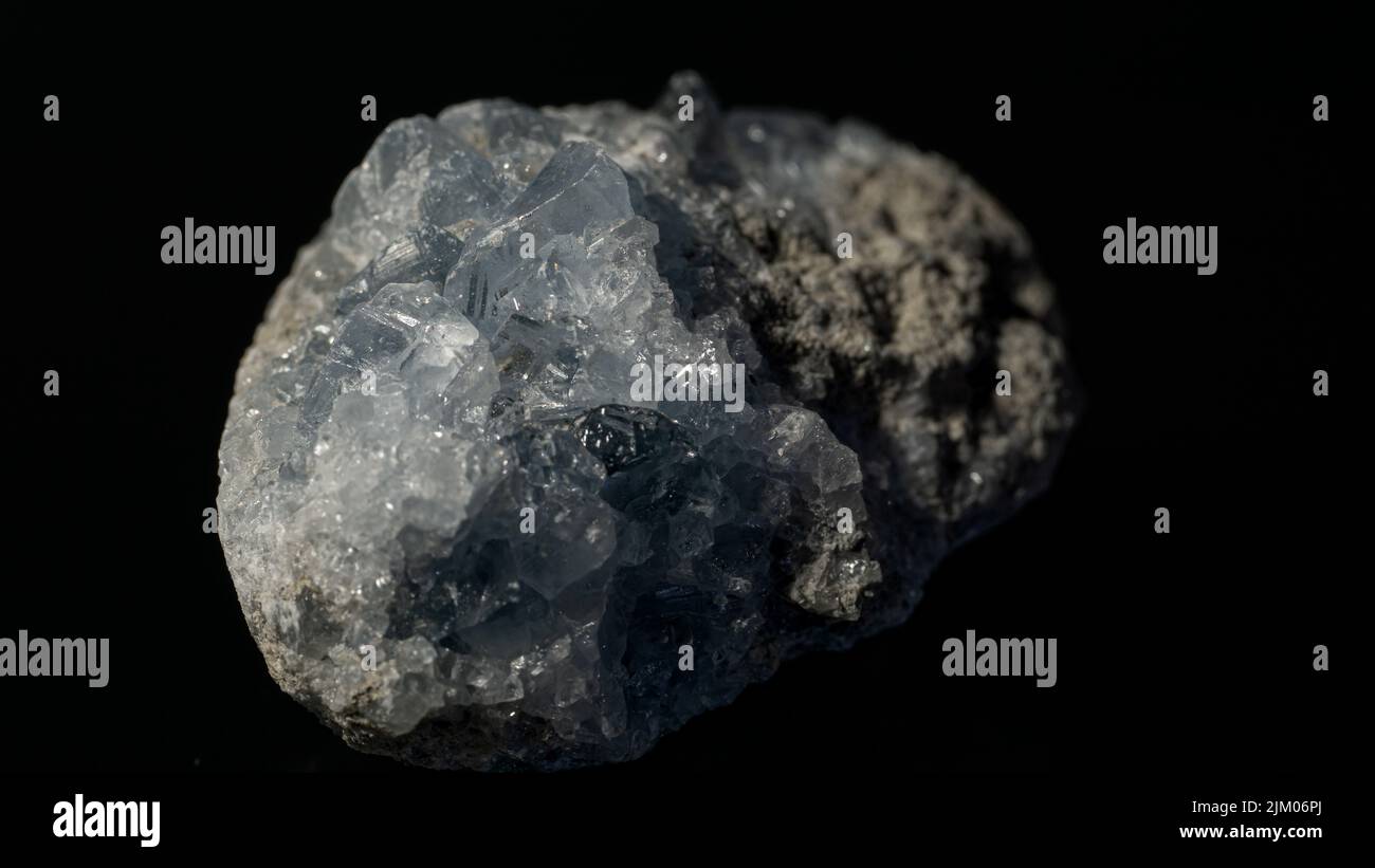 A closeup of sky blue celestine crystal gemstone on a reflective black ...