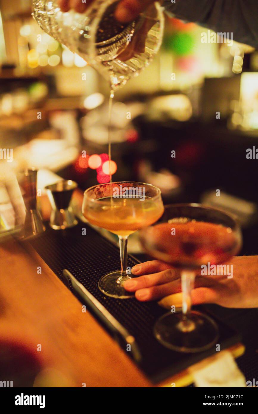 A vertical shot of a glass being filled with an alcoholic beverage in ...