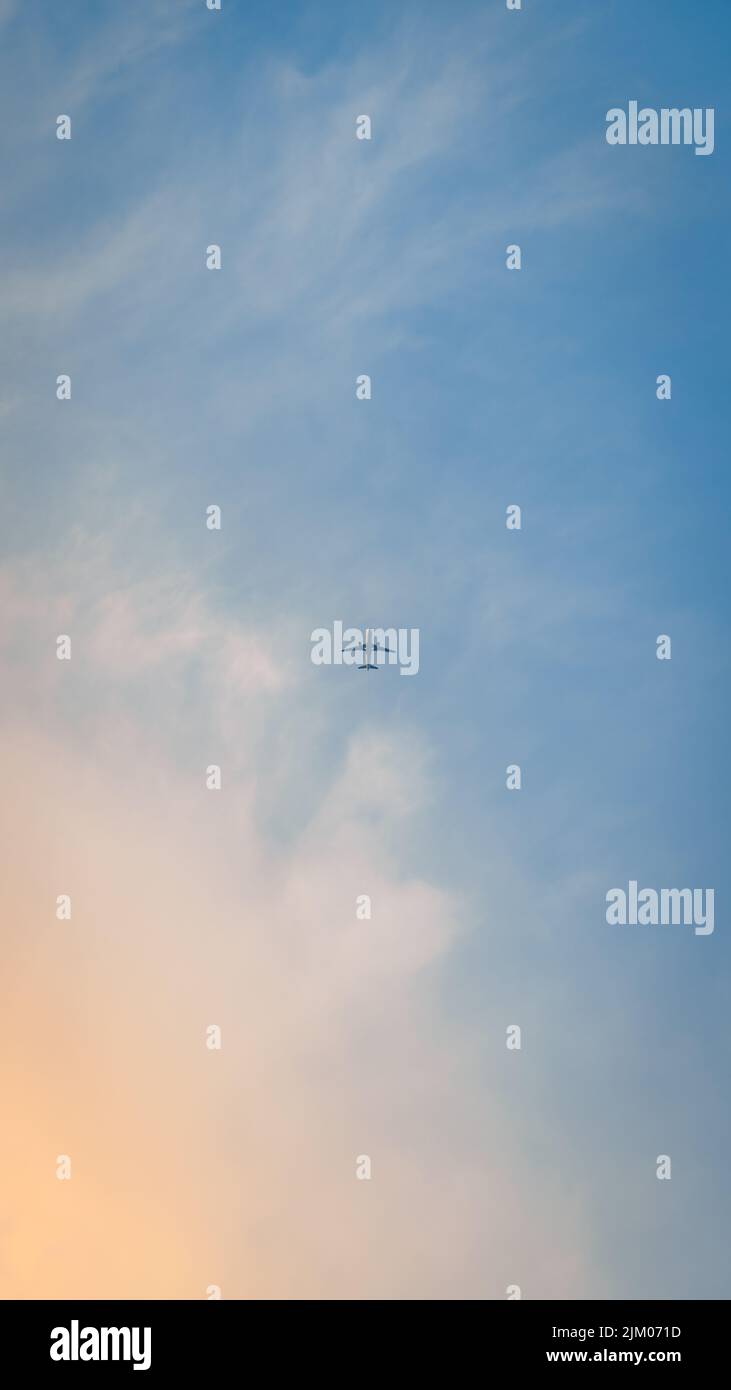 A vertical low angle shot of a passenger plain flying in the sky Stock ...
