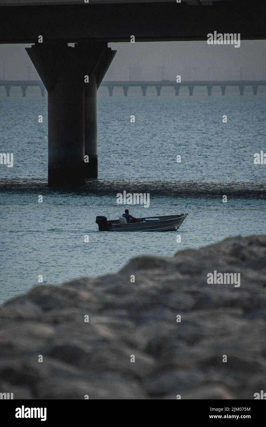 a vertical shot of man in small boat under the bridge Stock Photo - Alamy