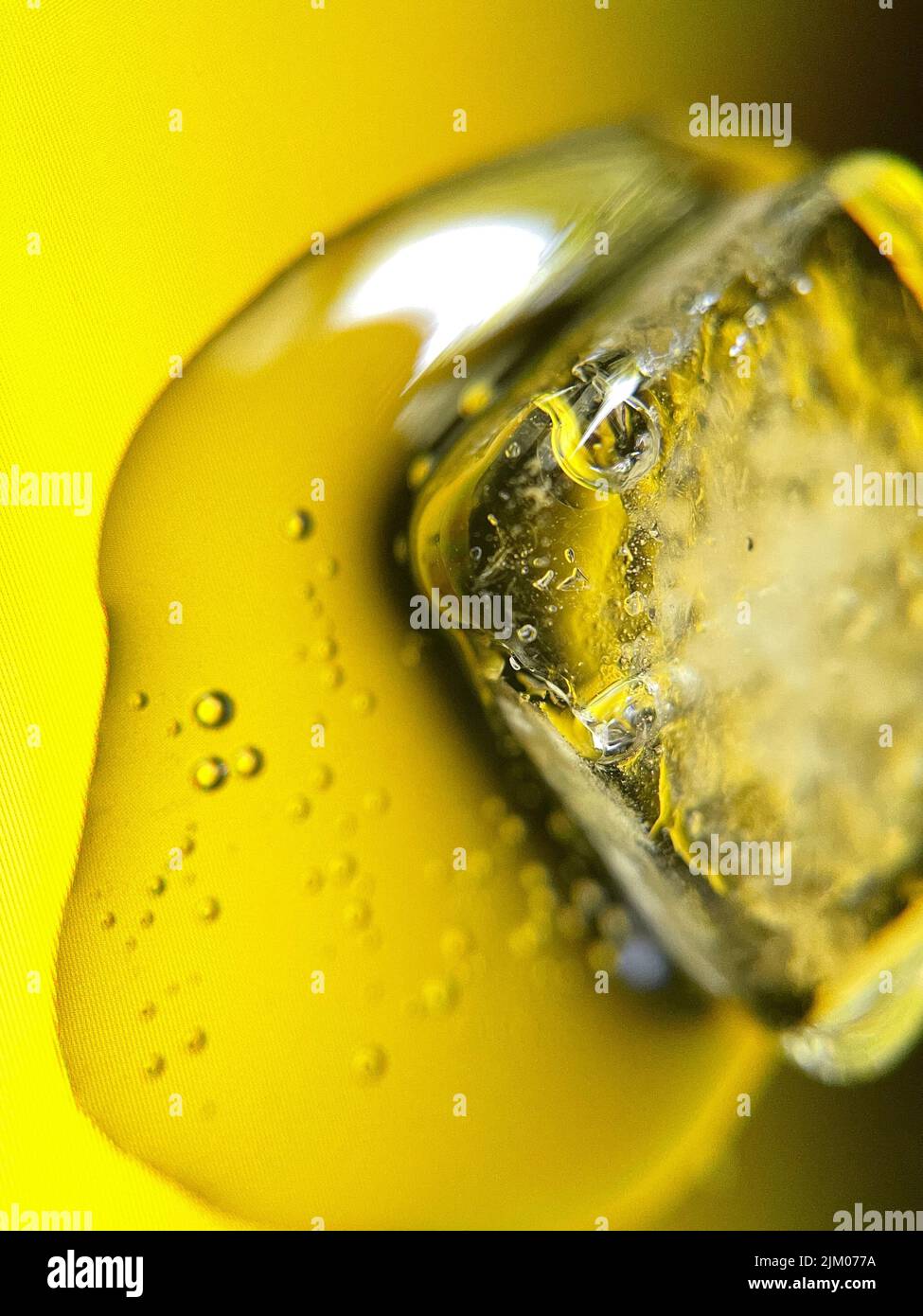 A vertical closeup of an ice cube melting on a yellow background Stock ...