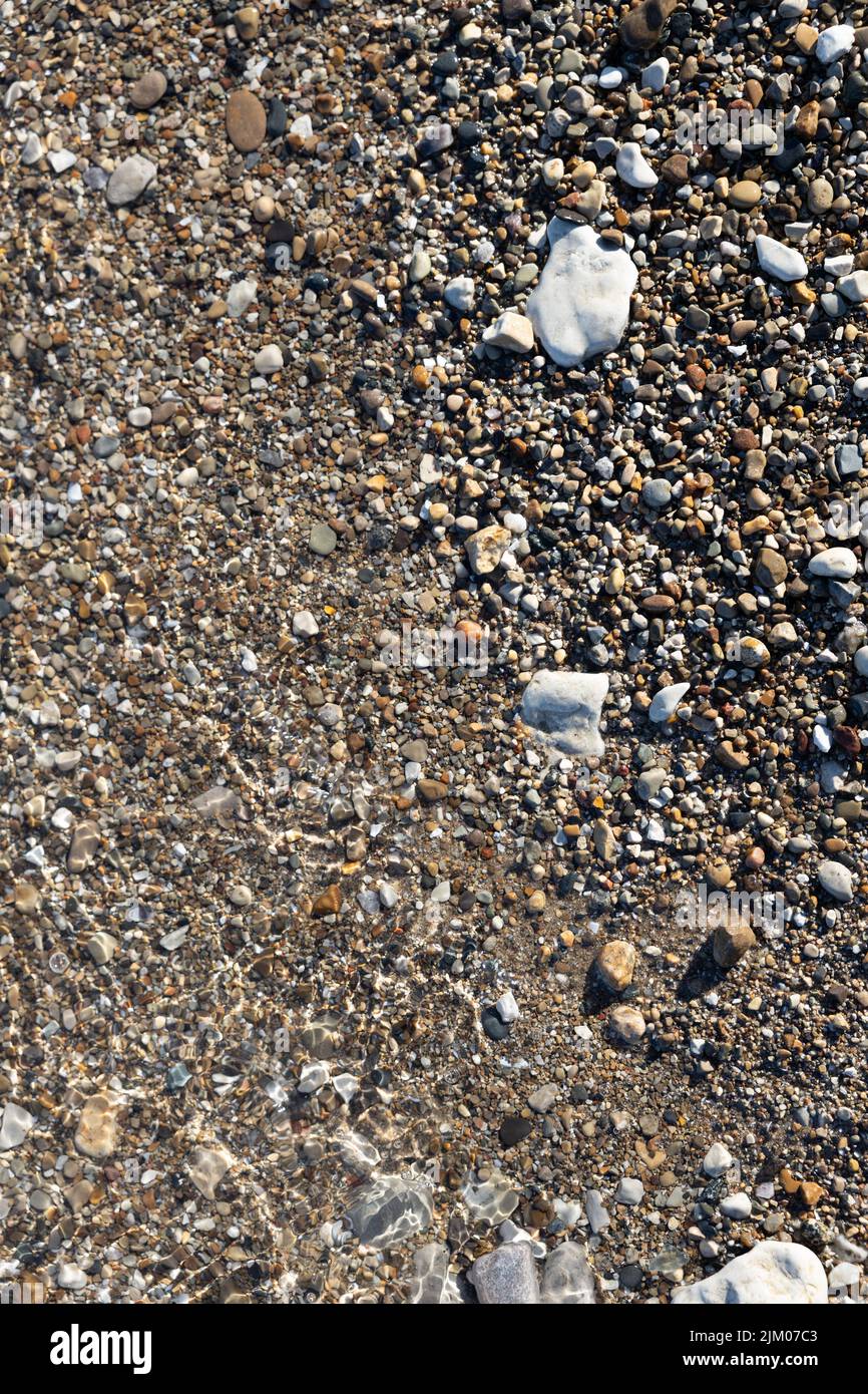 A top view of the sands with shells and stones on a beach in the ...