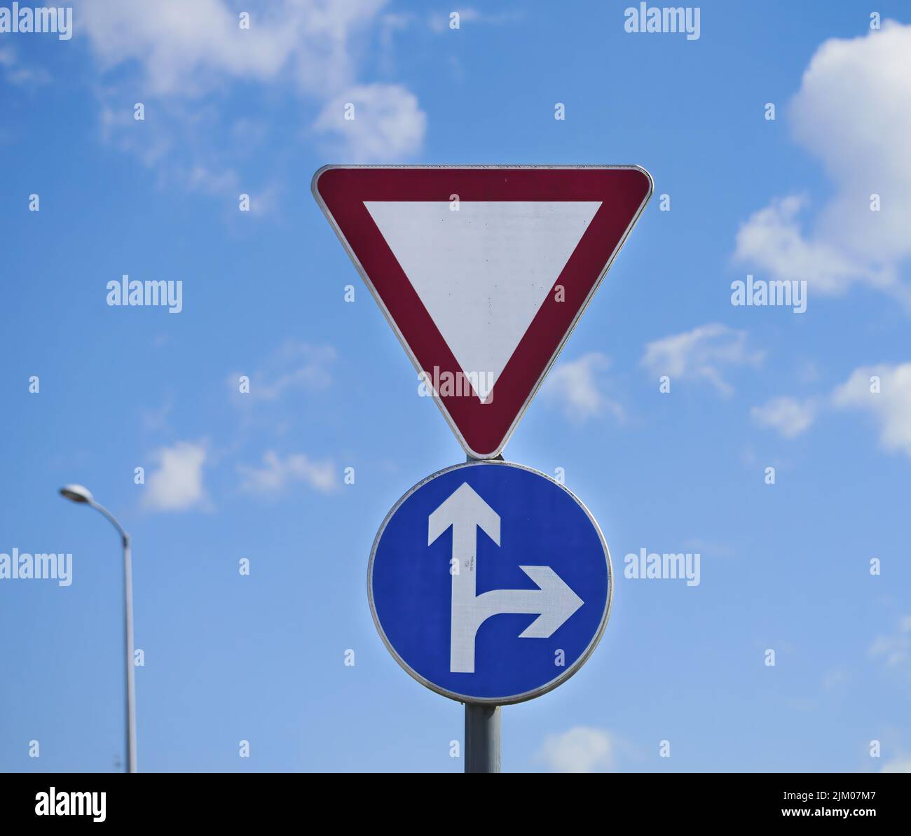 A red yield sign and a direction sign underneath on a pole Stock Photo ...