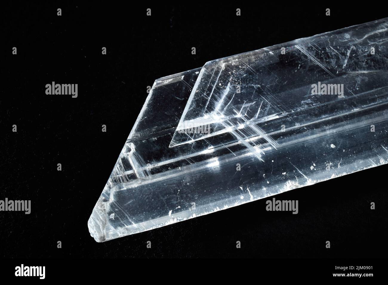 A closeup of a rare mineral row uncut transparent crystal on a black ...