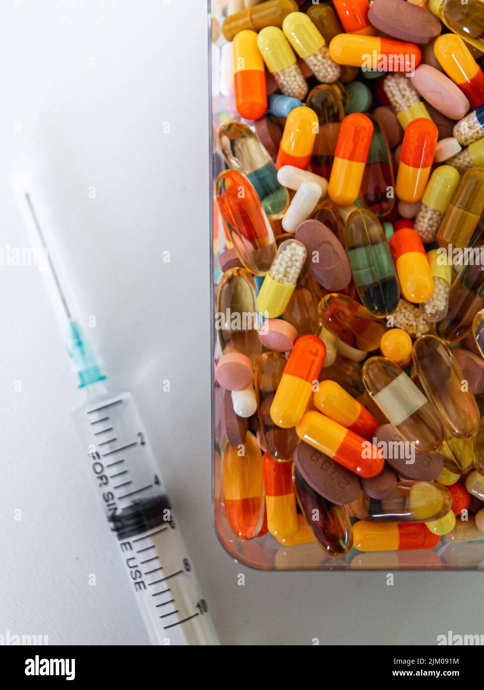 A bunch of medicinal pills next to a filled syringe Stock Photo - Alamy