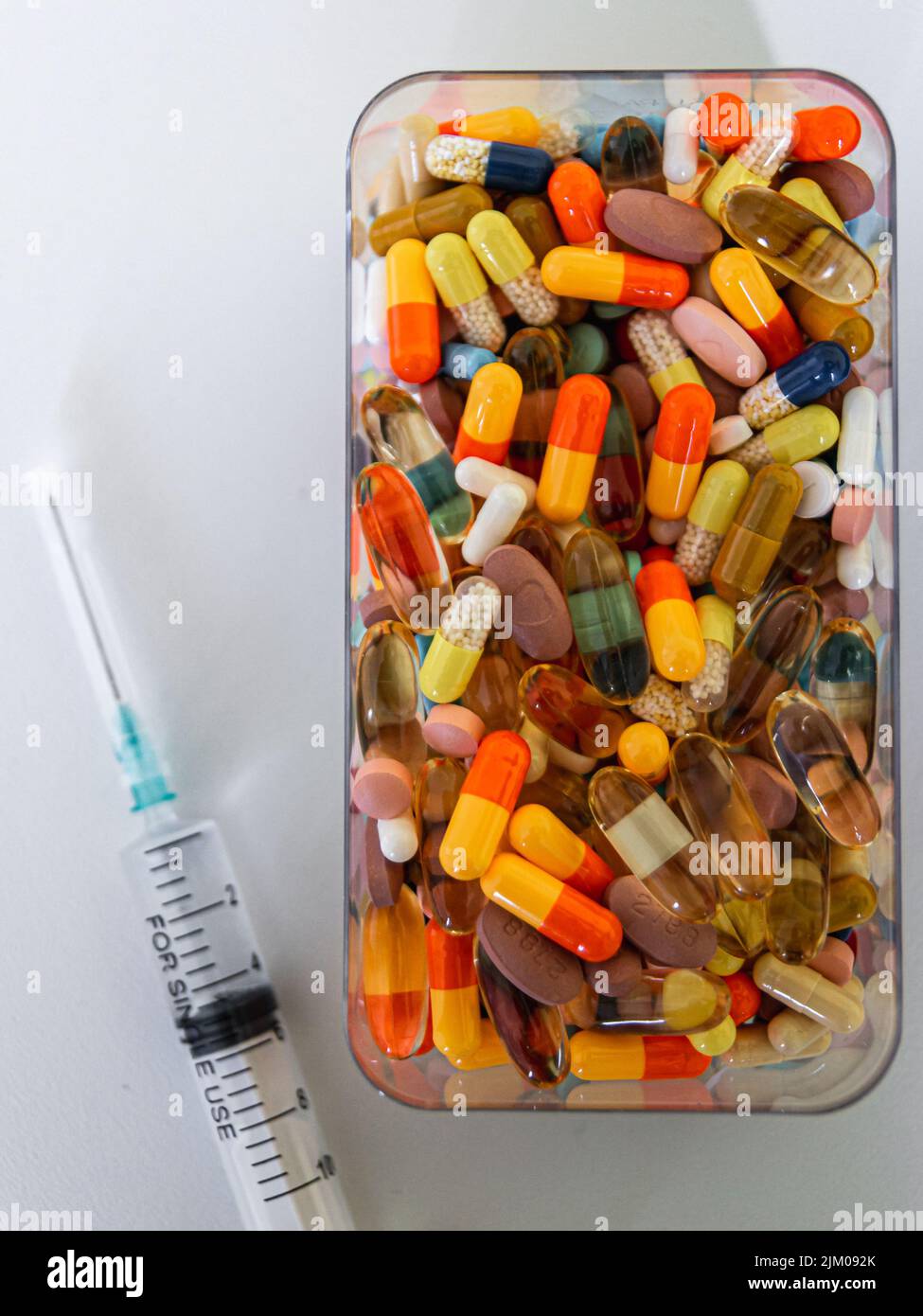 A bunch of medicinal pills next to a filled syringe Stock Photo - Alamy