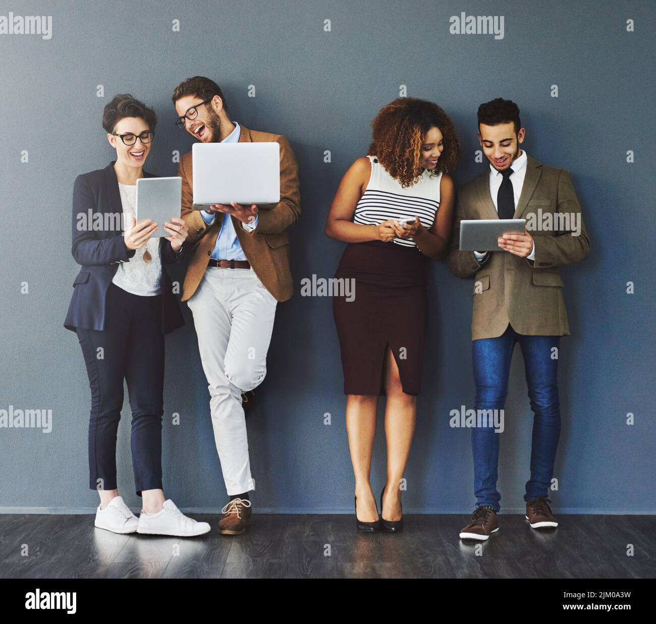 Happy workers using digital devices standing together on a work break ...