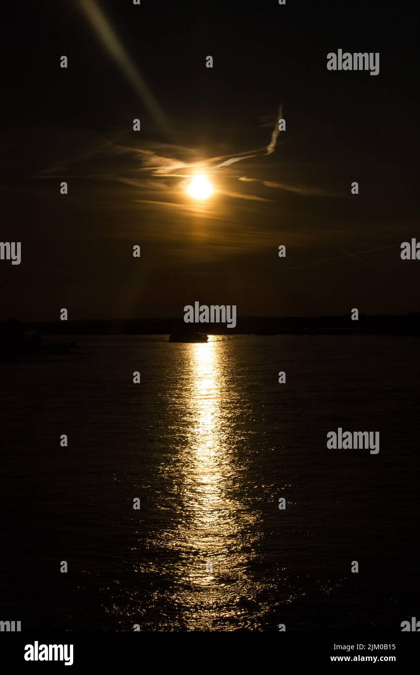The vertical shot of a lake view with sunlight on the water at sunset ...