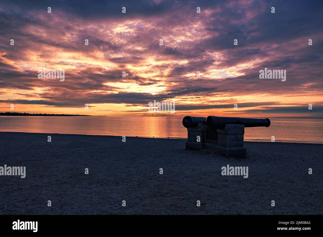 A big cannon on the beach and a beautiful sea at an orange sunset Stock ...