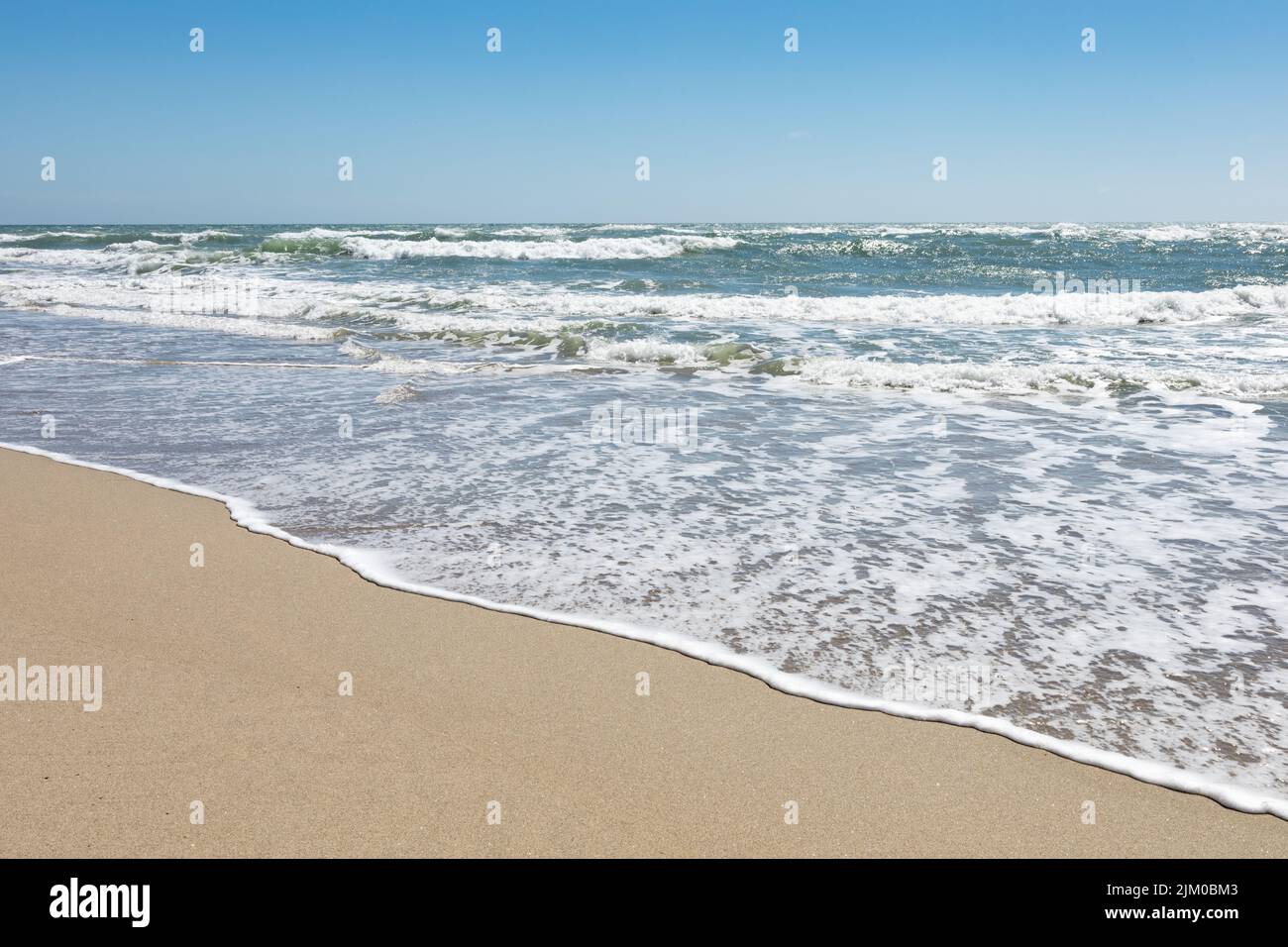 A beautiful landscape view of ebb and flow on a sandy beach with blue ...