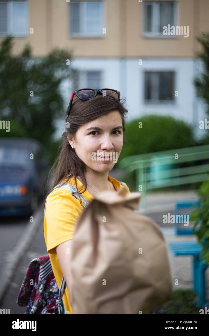 A girl holds out a paper bag with a purchase on the street. Delivery ...