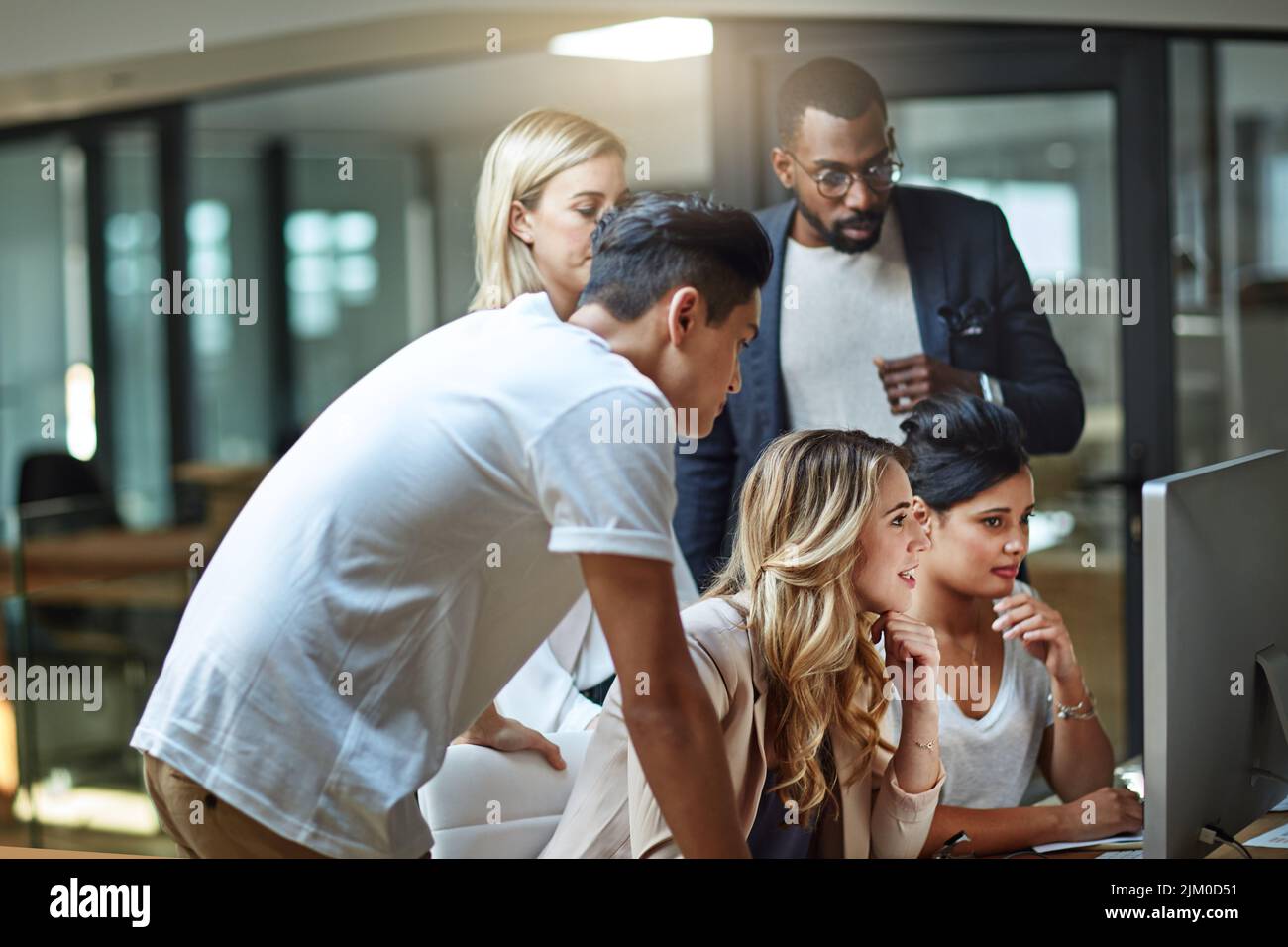 Diverse team of business people looking at a computer screen together ...