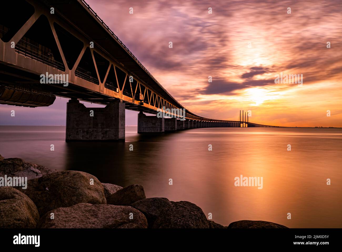 A low angle shot of a bridge over the sea on a golden sunset sky ...