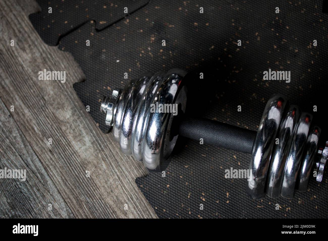 A closeup of a big steel dumbbell with a black handle on the ground in ...