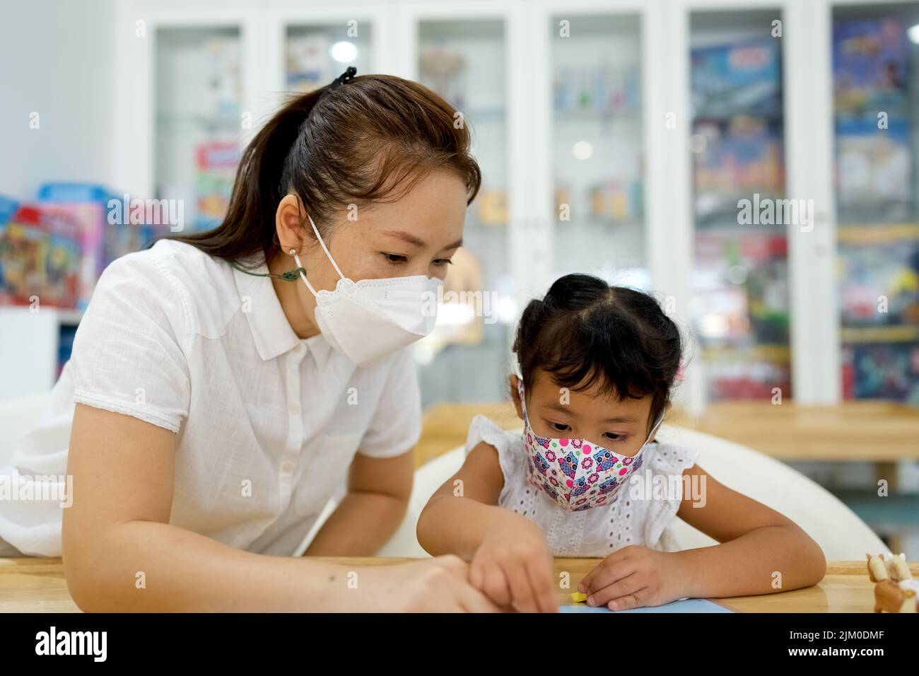 A mother and daughter with protective face masks playing with plastic ...