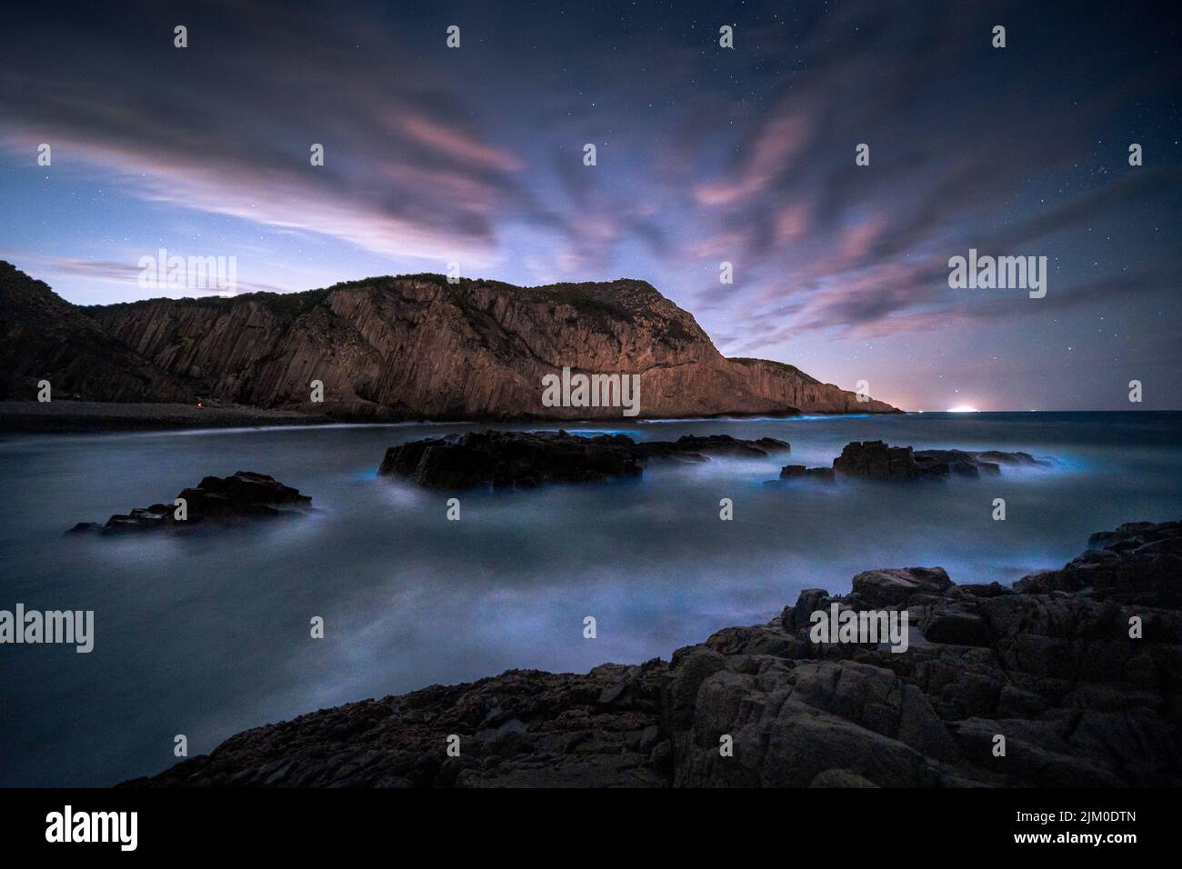 A bright purple sunset sky over a river near a mountain Stock Photo - Alamy