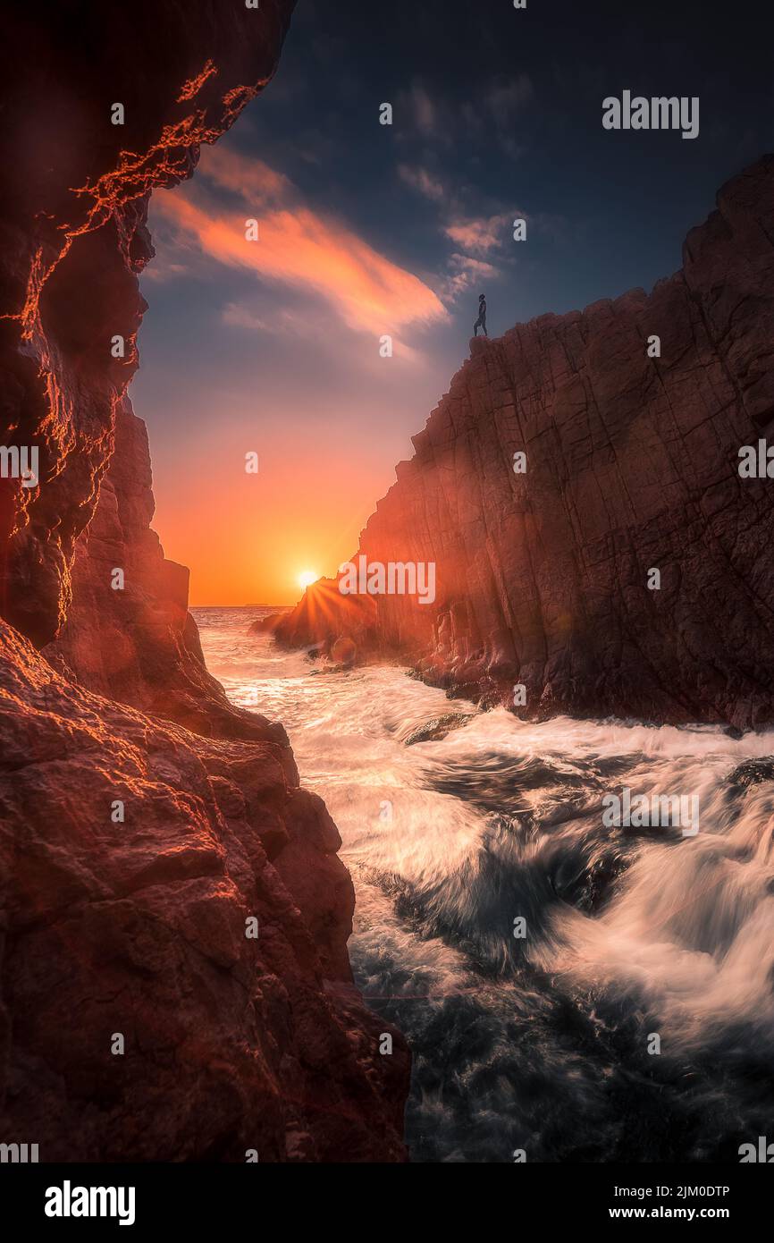 A vertical shot of a sunset over a flowing river near cliffs with a ...