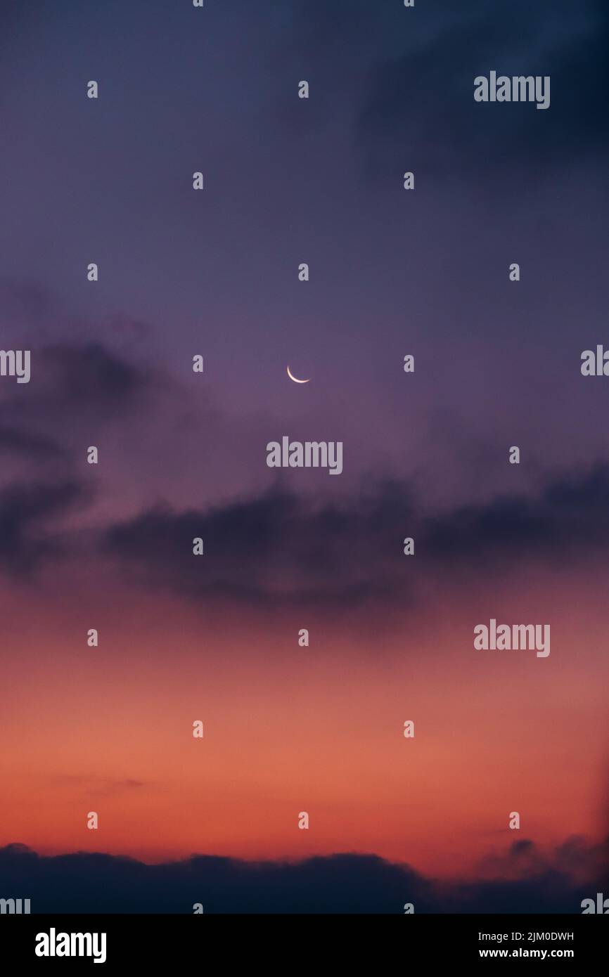 A vertical shot of a crescent moon in a bright sunset sky Stock Photo ...