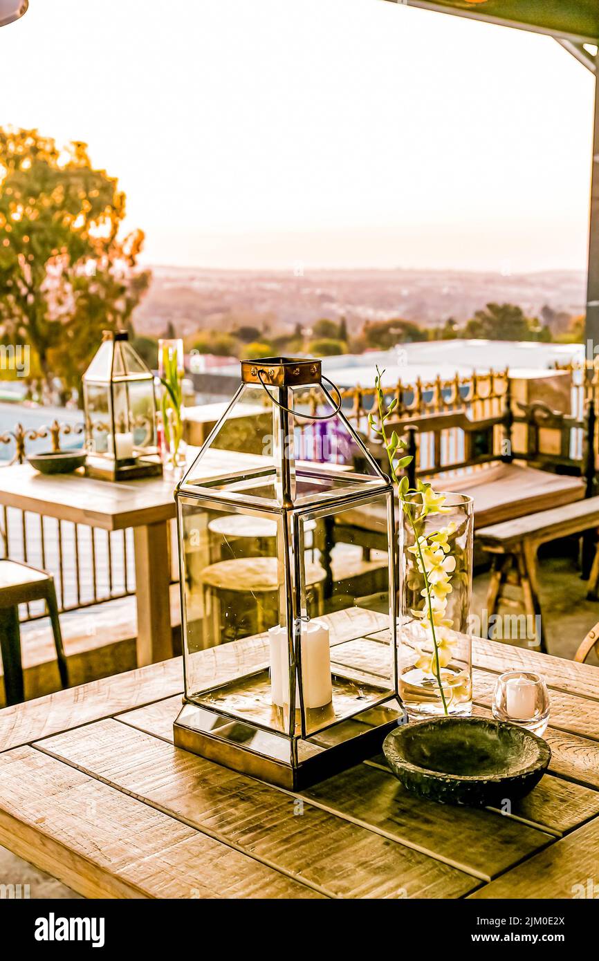 A candle inside glass lantern and cylindrical vase with a flower on the ...