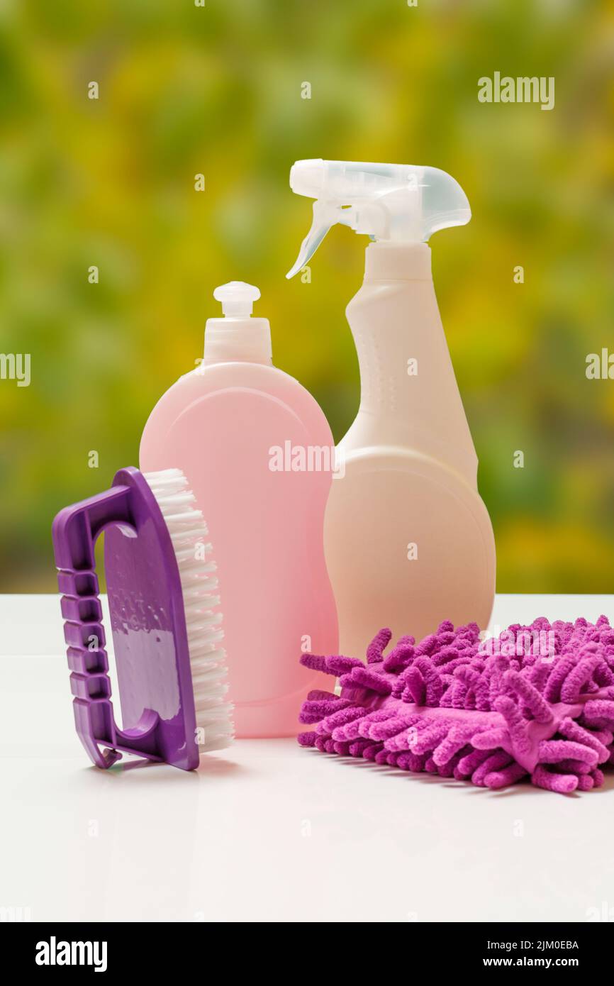 Bottles of washing liquid, a brush and a rag with blurred autumn leaves ...