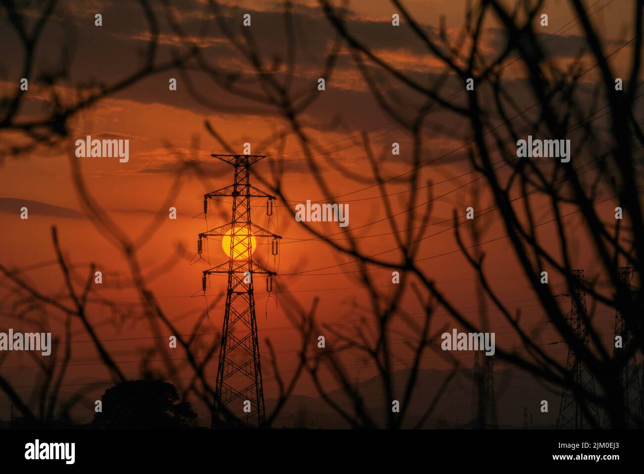 A scenic shot of an electric power tower under the golden sunset and ...