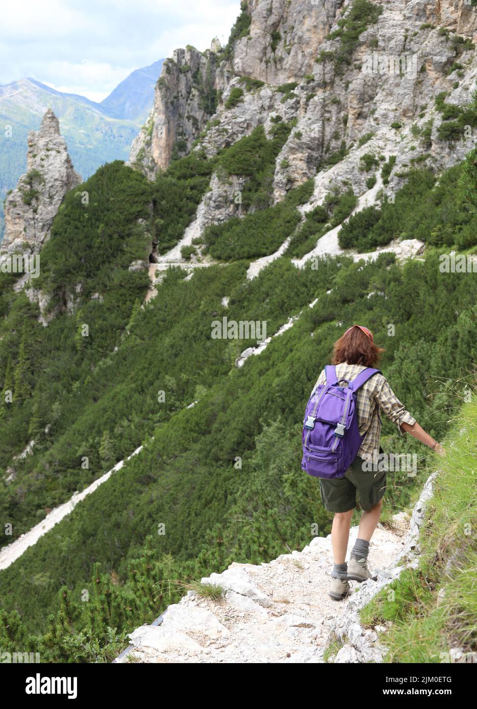 young girl with backpack walks along a high mountain trail in northern ...