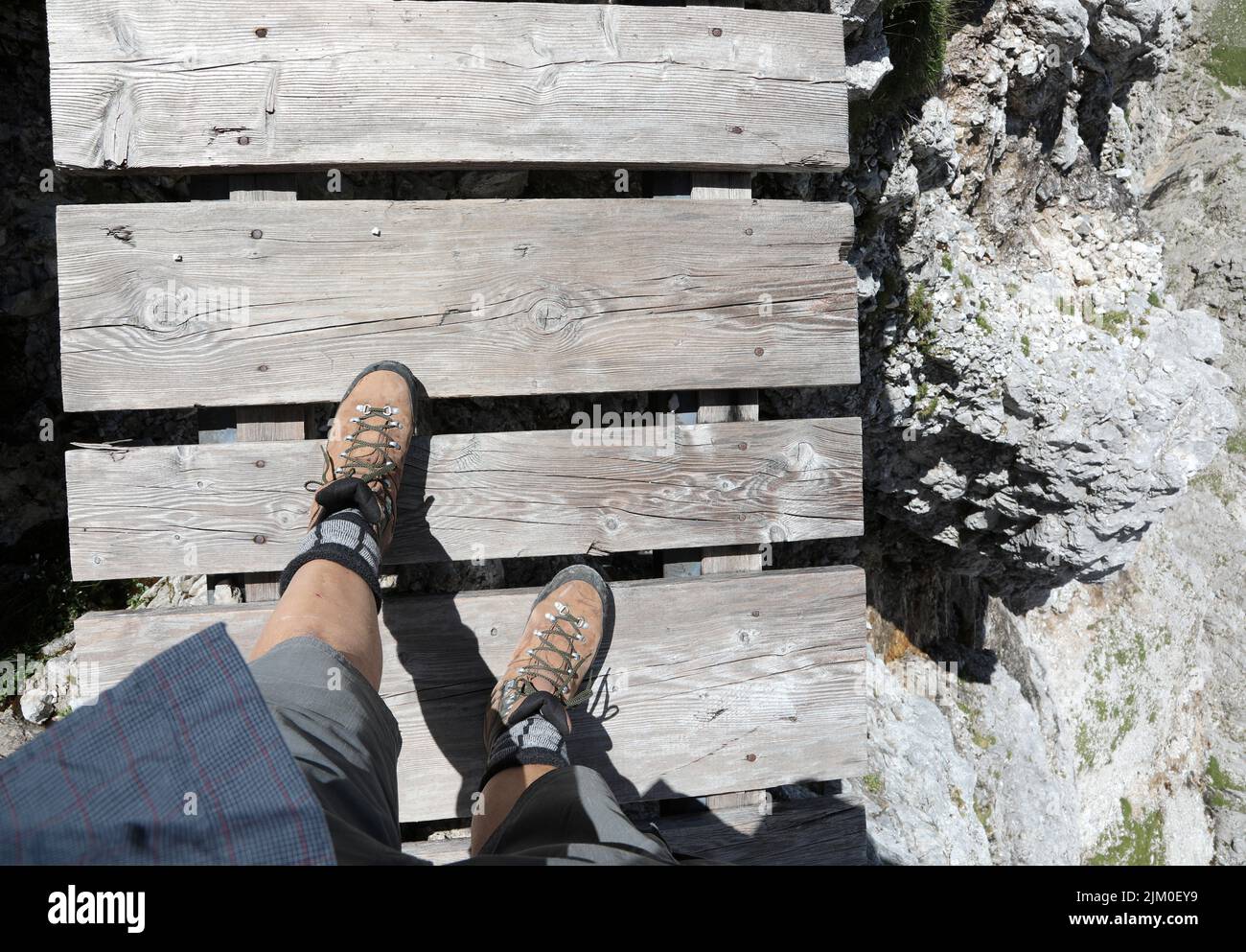 legs in the hiking boots of the walker as he passes over a wooden ...