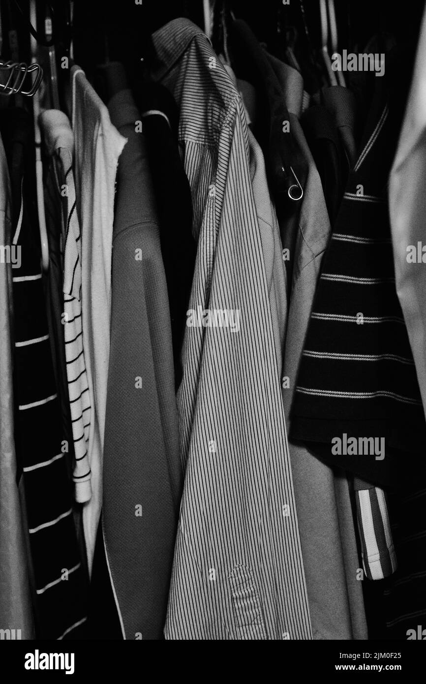 A vertical grayscale shot of clothes hanging in a wardrobe Stock Photo ...