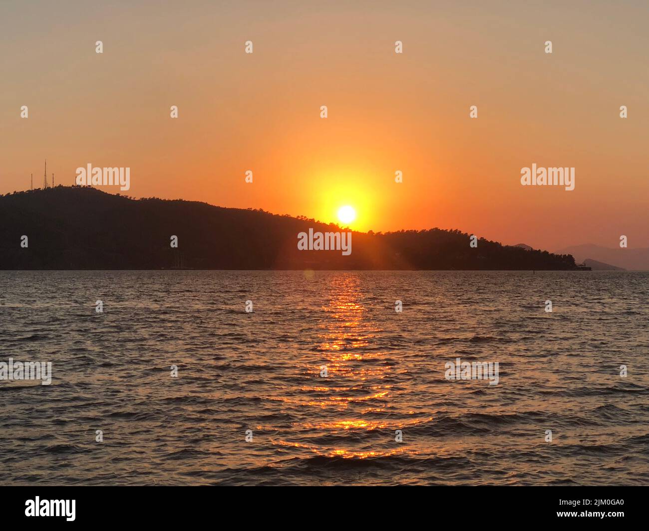 A beautiful scenery of the sunset behind the mountains with a sea in ...