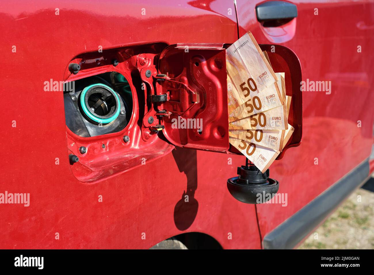 An open fuel tank of a car with a bundle of fifty euro banknotes in the ...