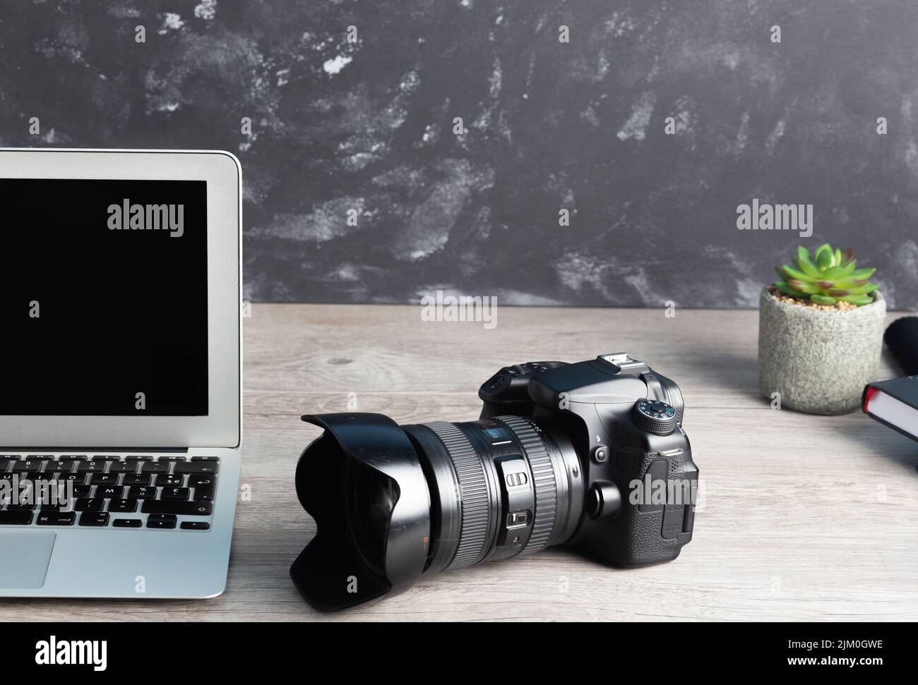 The photographer workstation with a camera, laptop, potted plant on the ...