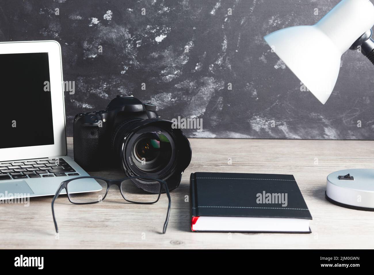 The photographer workstation with a camera, laptop, glasses on the ...