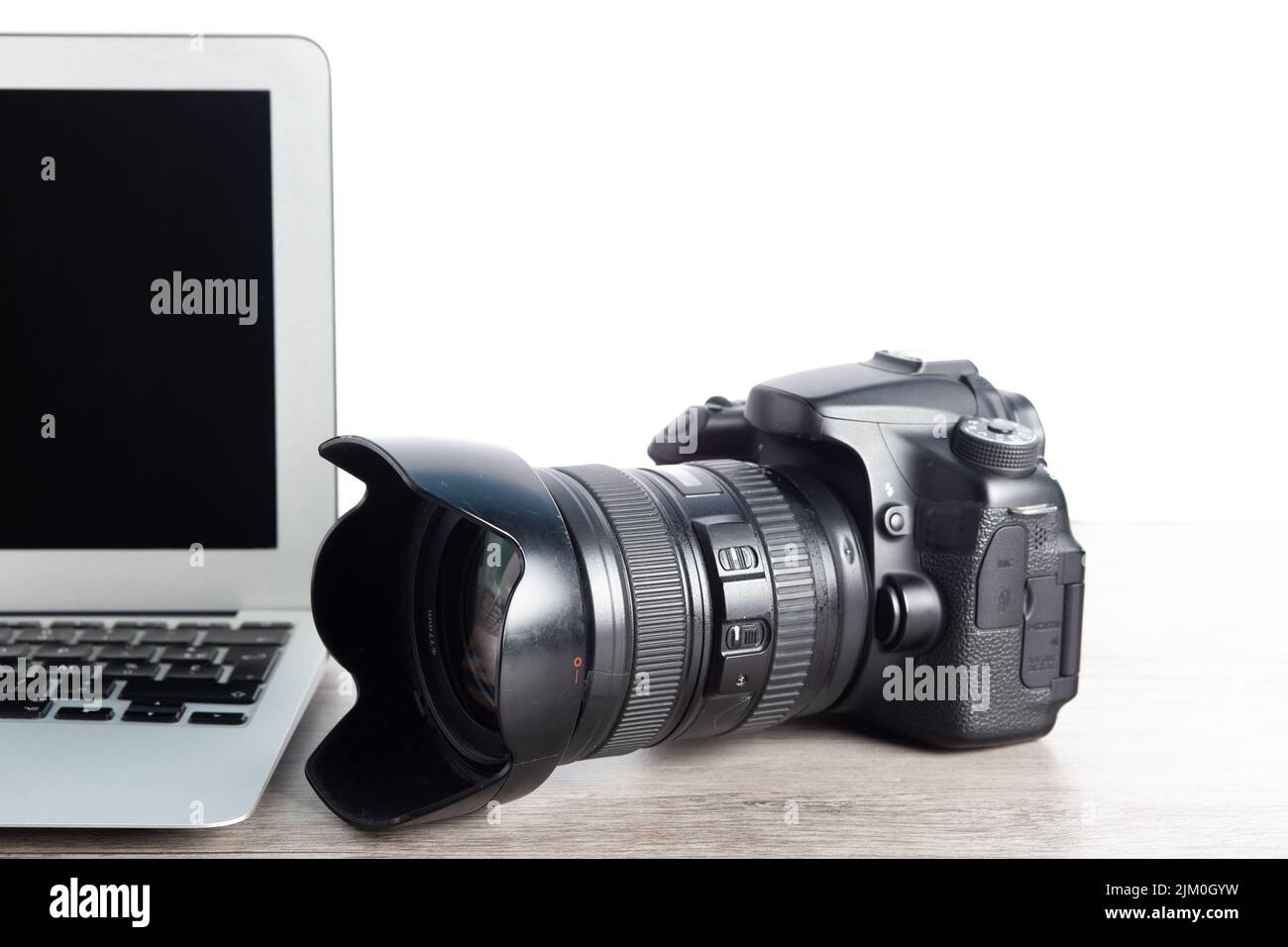 The photographer workstation with a camera, laptop on the wooden table ...
