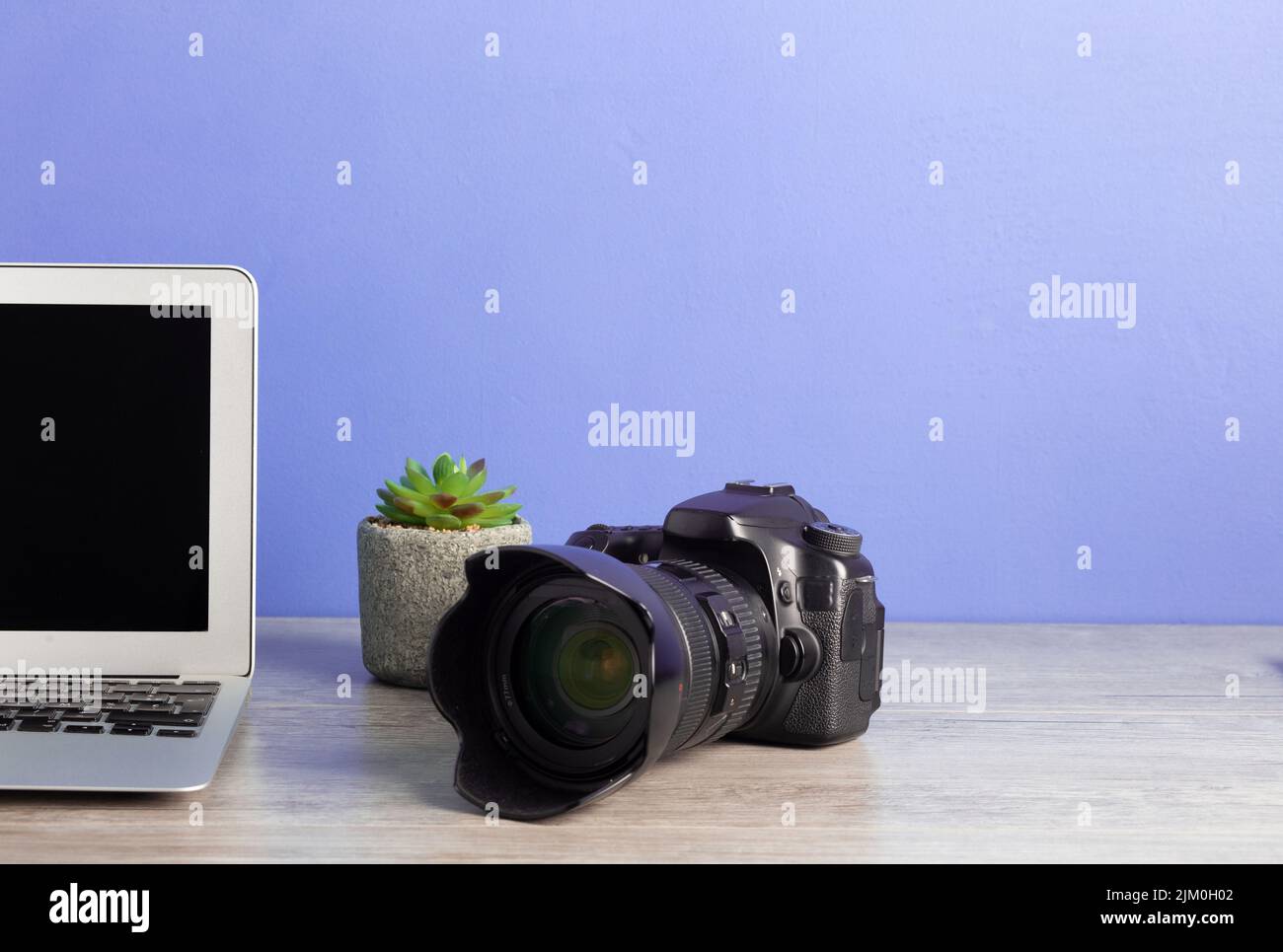 The photographer workstation with a camera, laptop, potted plant on the ...