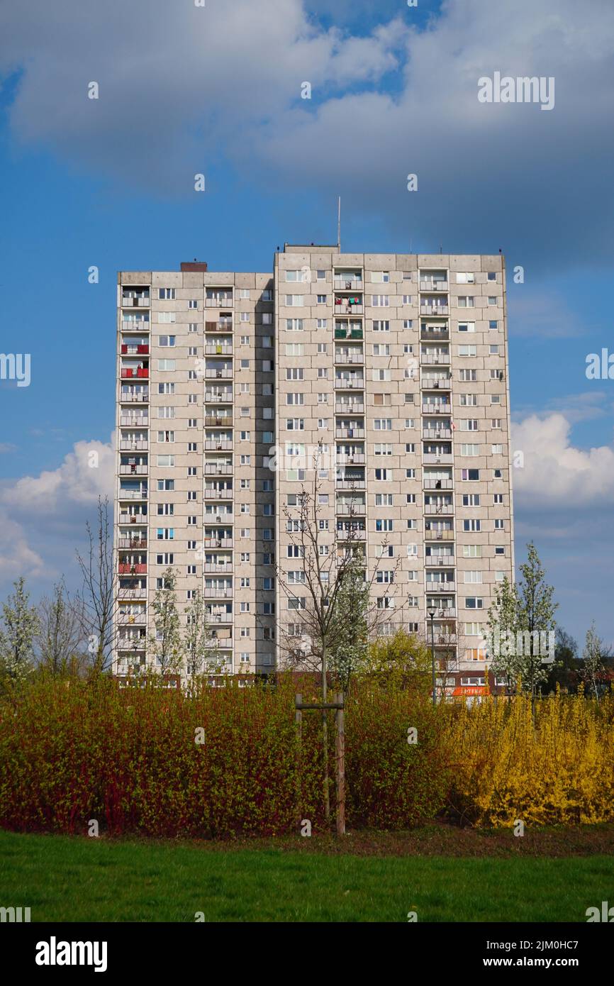 A vertical shot of tall apartment blocks near a green grass field in ...
