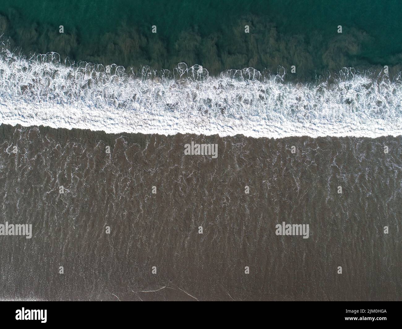An aerial view of soft ocean waves on a sandy beach in Costa Rica Stock ...