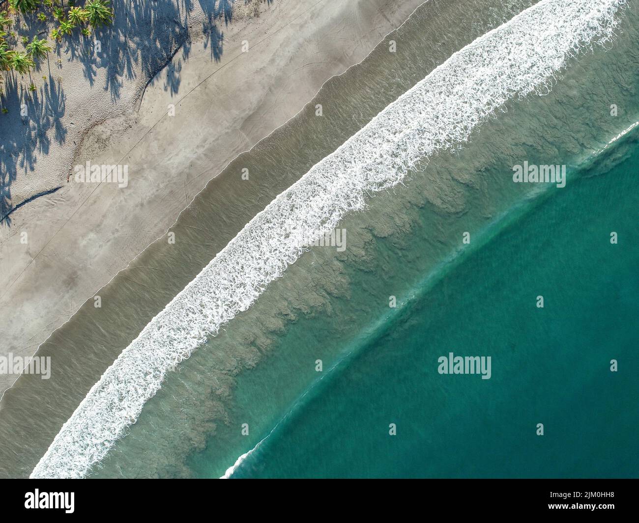 An aerial view of soft ocean waves on a sandy beach in Costa Rica Stock ...