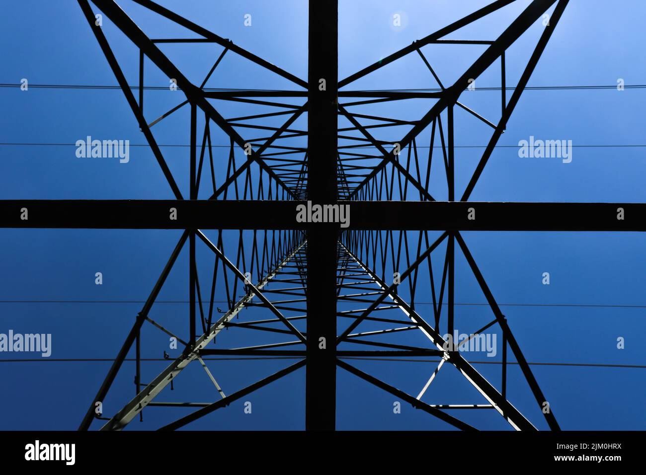 A low angle shot of a power line tower under a clear blue sky Stock ...