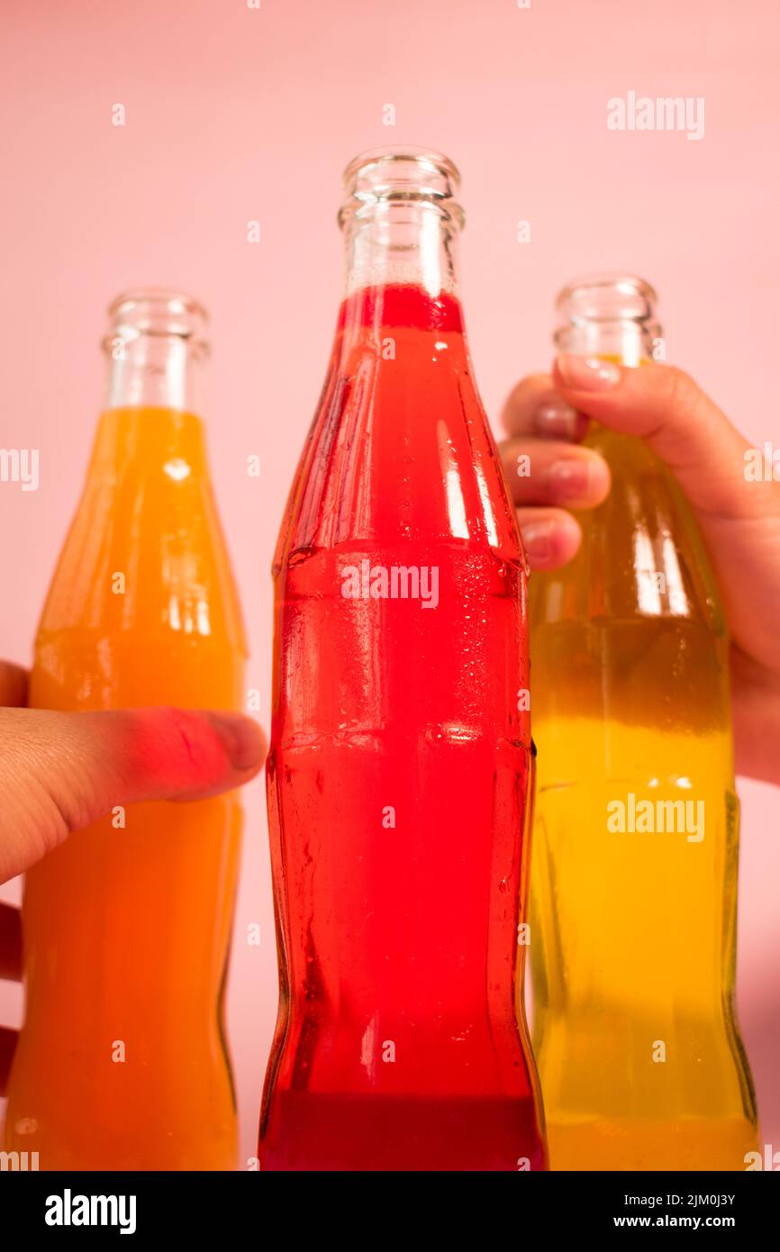 A vertical closeup of hands holding colorful soda drinks Stock Photo ...