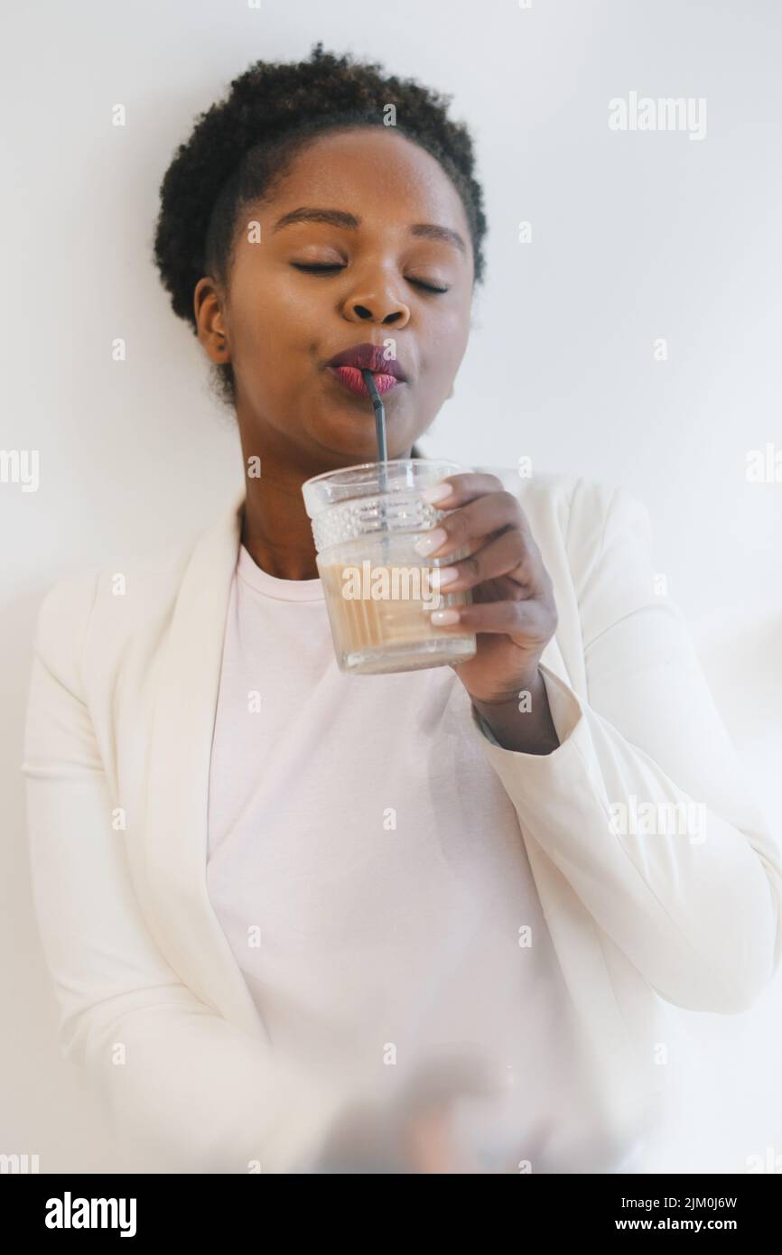 Beautiful woman drinking cold icy coffee in cafe from a glass jar ...
