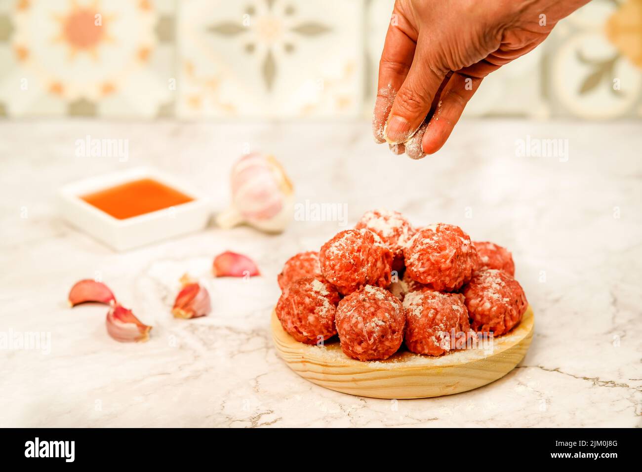 The minced meatballs with garlic on a wooden tray on a white marble ...
