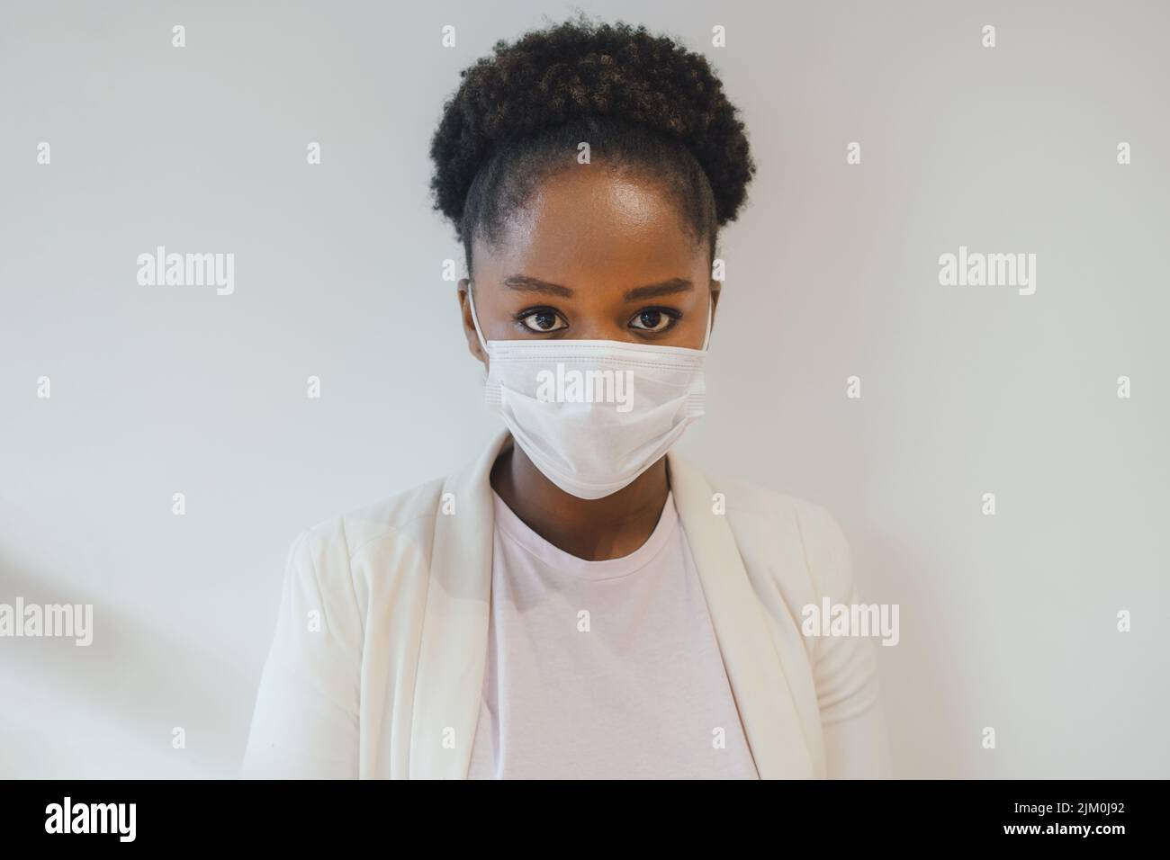 Portrait of afro businesswoman in medical face mask being on self ...