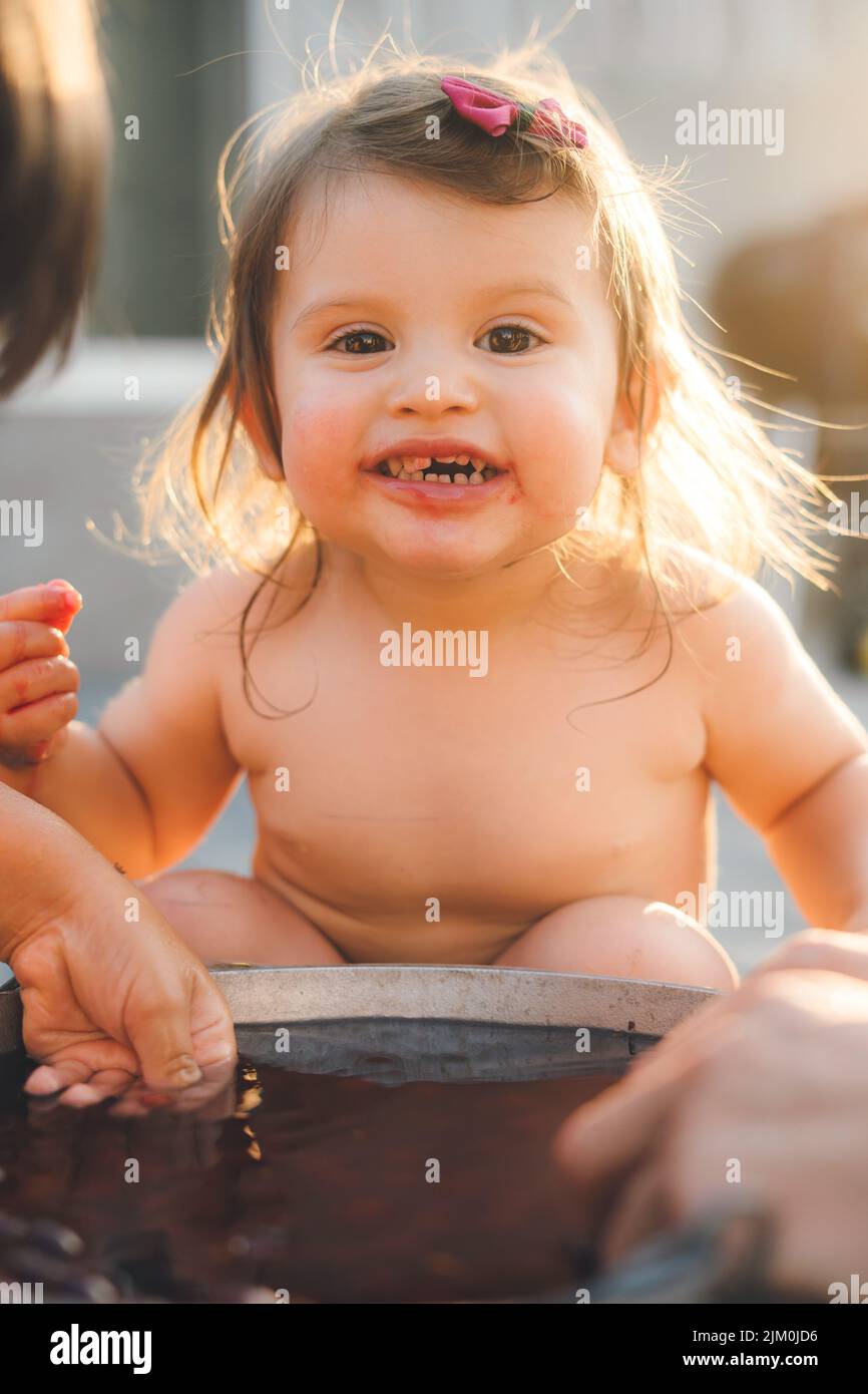 Baby girl eating cherries while washing them together with her mother ...