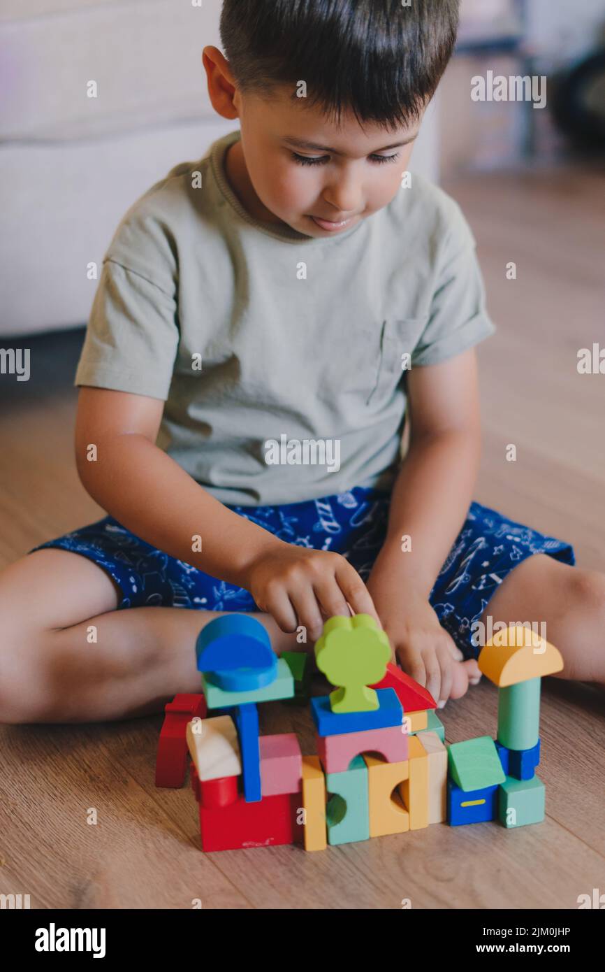 Lovely boy playing with building cubes sitting on the floor, children ...
