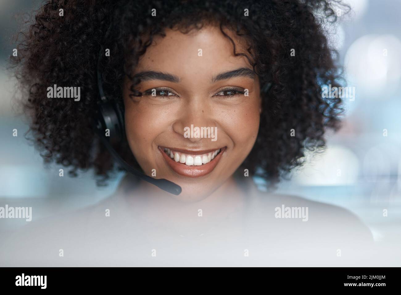 Webcam on. a young female agent smiling over her monitor with her ...