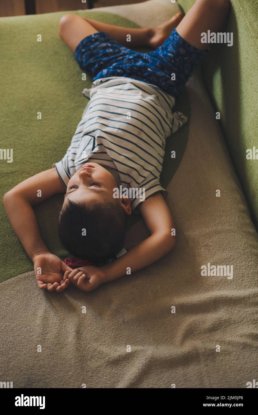 Portrait of boy laying on her back, on sofa at home. Family concept ...