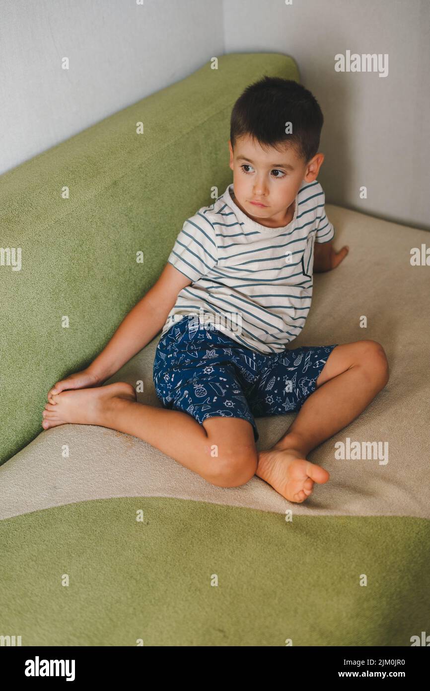 Preschooler boy relaxing and resting comfortable on the green couch in ...